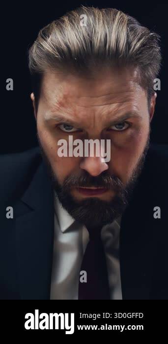 A man in a suit stares intently into the camera with a fierce ...