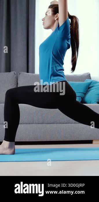 At home, a woman practices her stretching routine to enhance ...