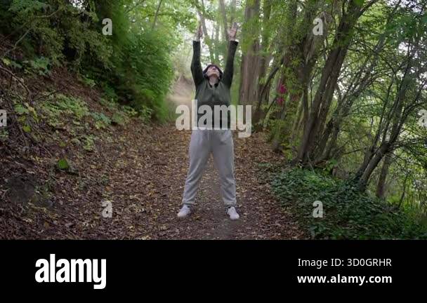An older woman joyfully exercises on a trail in a lush forest ...