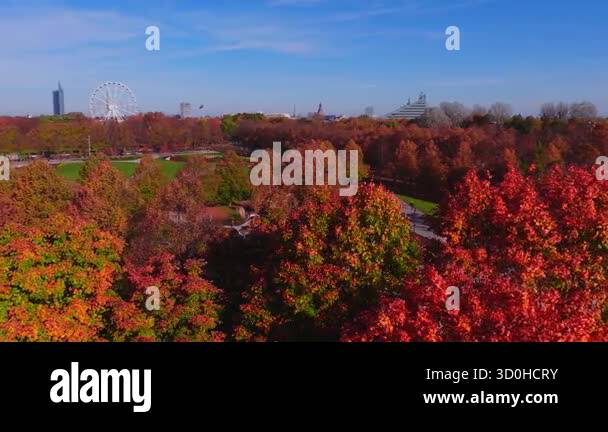 Aerial pan and slight descent over a Riga park in autumn, with red and ...