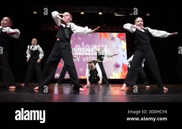 A youth dance ensemble in black overalls performs expressive ...