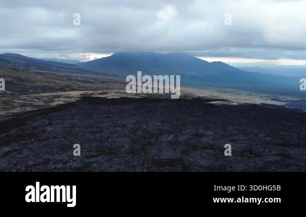 Aerial view flying over a vast volcanic lava field in iceland towards a ...