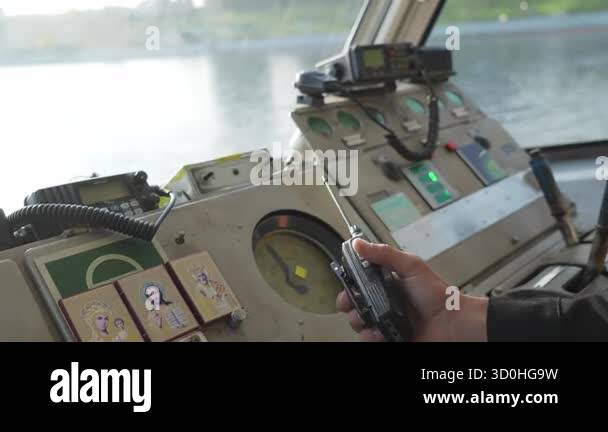 Young male sailor in uniform navigating a boat and speaking into a ...