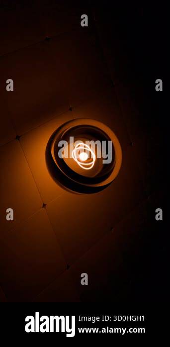 Glowing orange atom symbol spinning inside a glass sphere on a dark ...