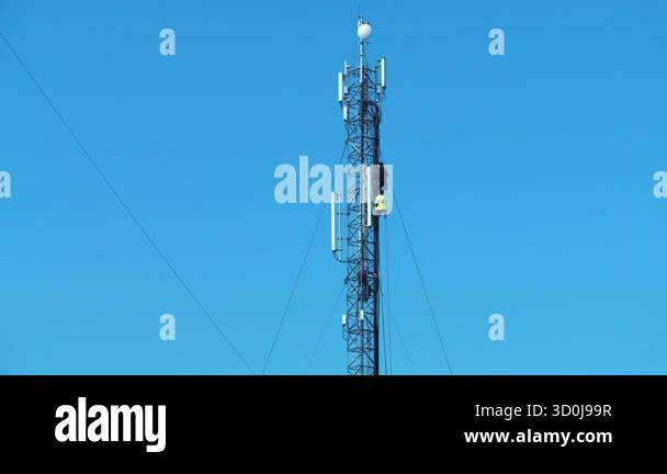 Cell tower on blue background. High-altitude work. Two workmen on cell ...