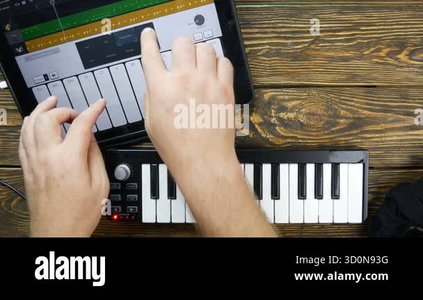 Playing on the midi keyboard. Midi Keyboard and tablet on a wooden ...