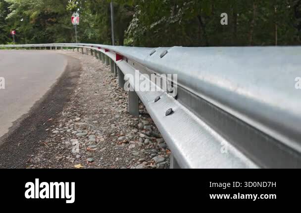 Close up of a metallic road barrier perspective along a winding road ...