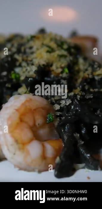 Close up view of black ink pasta with shrimp and parmesan on white ...
