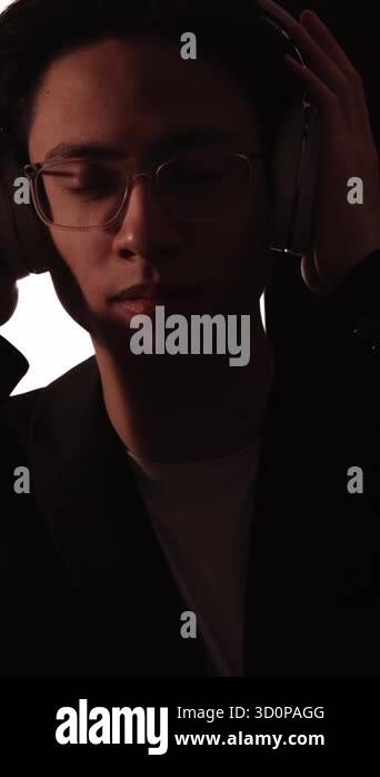 Vertical video. Music inspiration. Sound technology. Dark silhouette of relaxed man enjoying ...