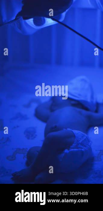 Close up of a newborn baby moving around on a crib mattress, wearing a ...