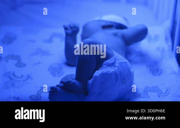 Close up of a newborn baby moving around on a crib mattress, wearing a ...