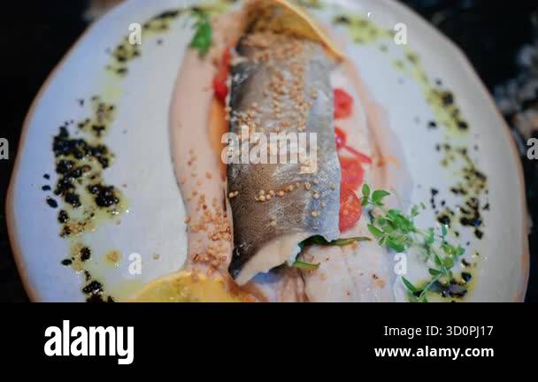 Close up of a beautifully plated fish fillet with sauce, lemon slice ...