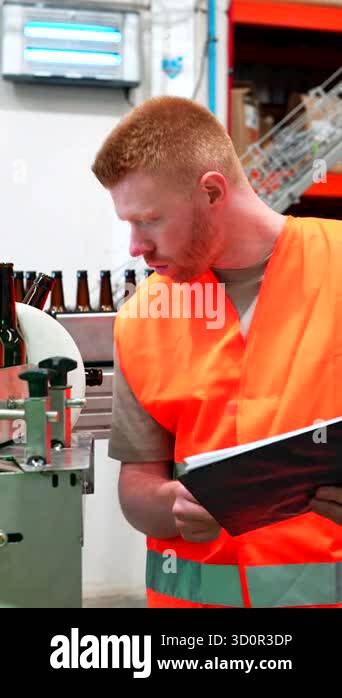 Diligent factory worker wearing a safety vest meticulously inspecting ...
