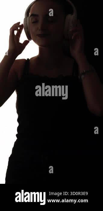 Vertical video. Music inspiration. Sound technology. Dark contrast silhouette of relaxed girl ...
