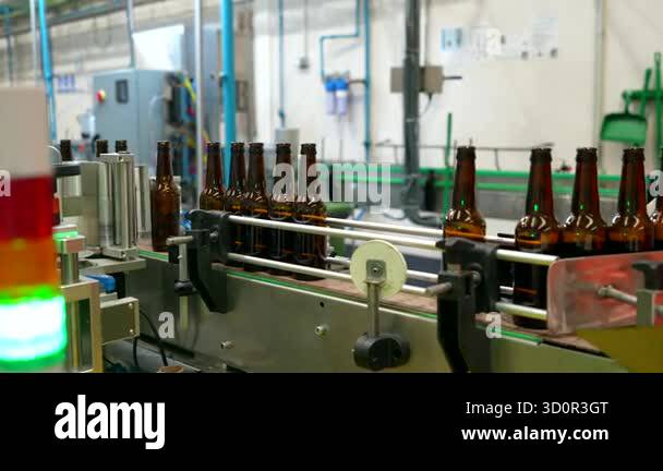 Empty brown glass bottles traveling along a moving conveyor belt system ...