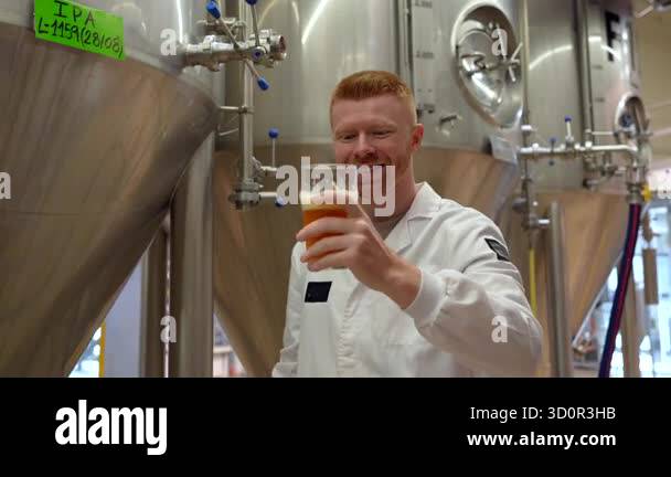 Professional brewmaster in a white coat pouring a sample of ipa from a ...