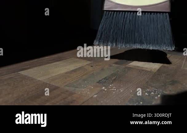 Close-up vertical video showing a broom sweeping dust, lint, and small ...
