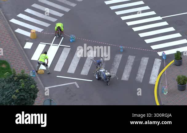 Applying road markings. Paint a pedestrian crossing with white color ...