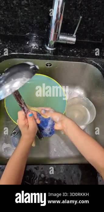 Child washing dishes at kitchen sink, learning family chores and ...