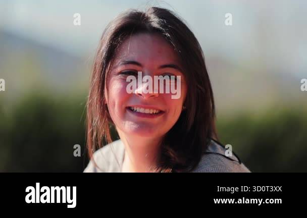 Smiling white Hispanic woman looking to the side in soft daylight with ...