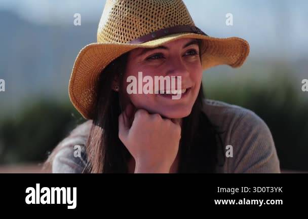 White Hispanic woman with straw hat smiling and resting chin on hand ...