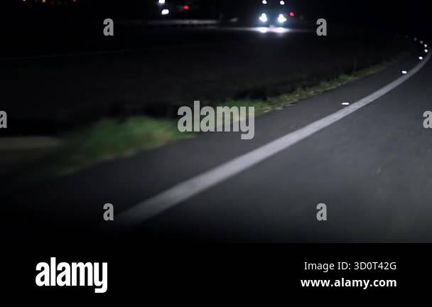 View of roadside shoulder at night with vehicles on opposite side ...