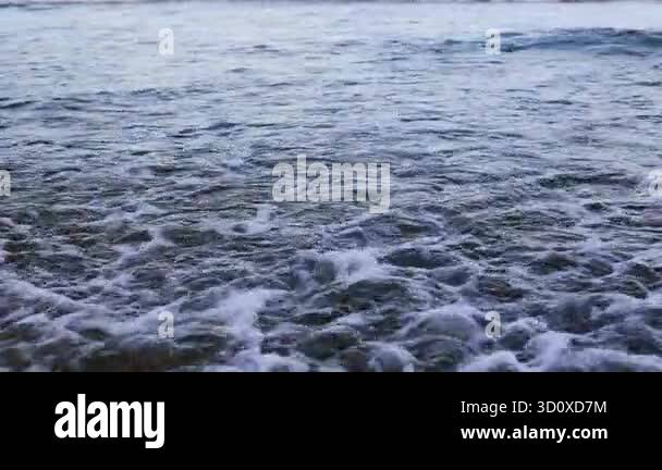 Dynamic ocean waves gently recede on sandy shore during golden hour ...