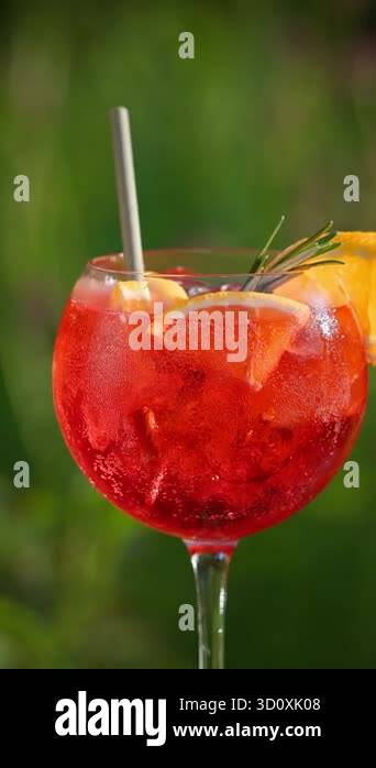 human hand take a glasss of classic red spritz cocktail, green summer ...