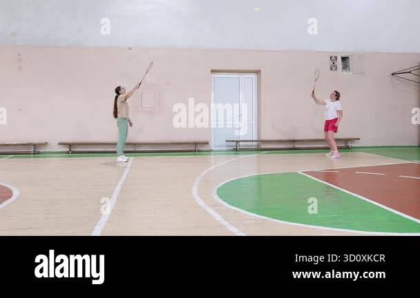 Two women playing badminton in a gym with a wooden floor Stock Video ...