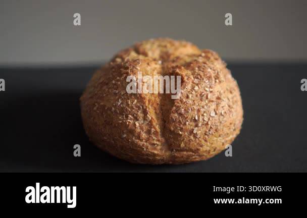 Rustic round bread roll with deep crack on crust filmed close up on ...