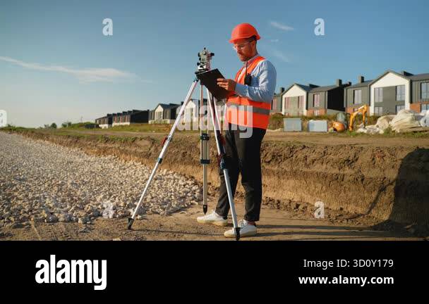 Professional land surveyor using a theodolite on a tripod and writing ...