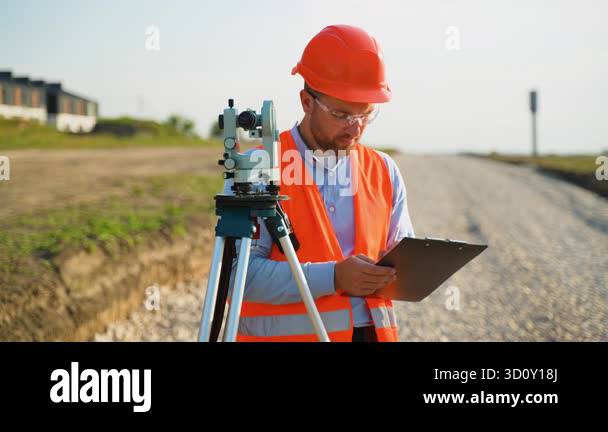 Professional surveyor working with a theodolite on a tripod, taking ...