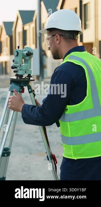 Male civil engineer working with surveying equipment on a tripod at a ...