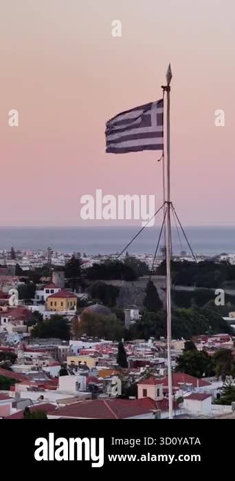 The national flag of Greece waves in the wind above Rhodes Town ...