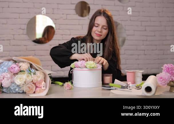 A female florist designs and arranges a stunning bouquet of fresh ...