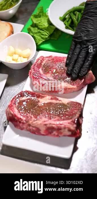Chef seasoning ribeye steak with herbs. Close-up of chef using rosemary ...