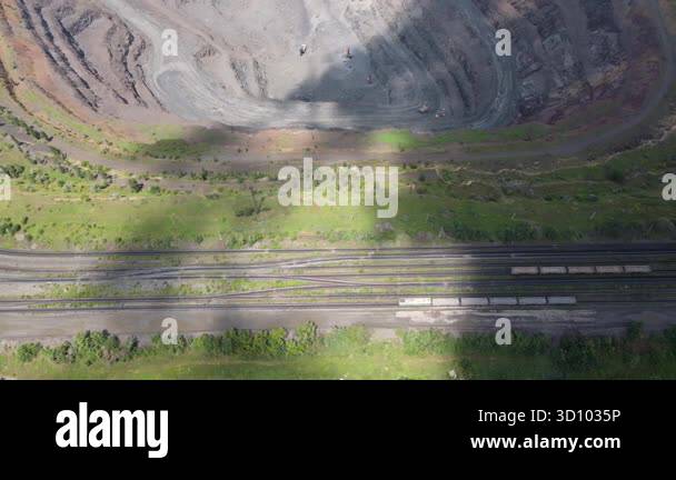 Aerial drone footage flying along railway tracks beside a massive iron ...