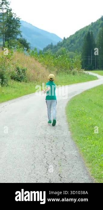 Child running along a path among the mountains, vertical slow motion ...