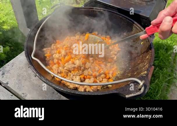 Traditional cauldron meal with onion and carrot frying outdoors showing ...
