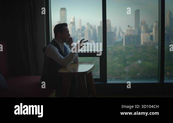 A thoughtful businessman is lost in reflection while holding a phone ...