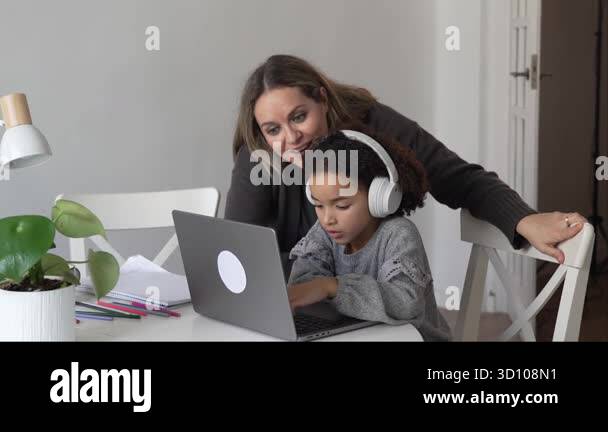 Caucasian mother and African American daughter studying at home, mom ...