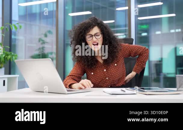 Upset businesswoman suffering from back pain while working on laptop ...