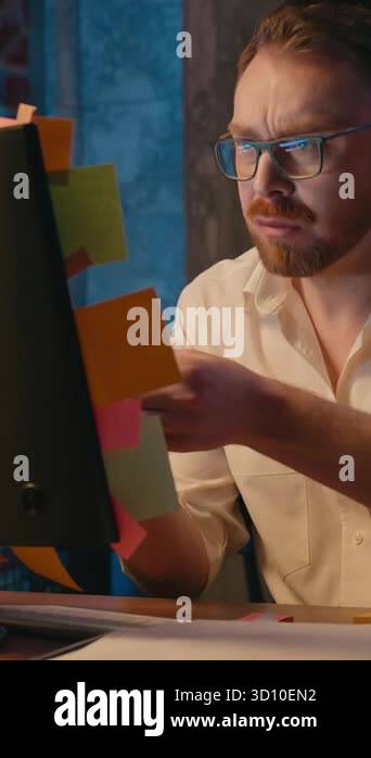 Tired Caucasian man business in night office managing sticky notes on ...