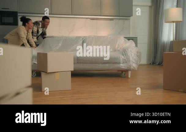 Carefree African American couple pushing new couch sofa at renting home ...