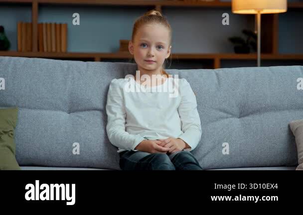Calm relaxed cute Caucasian child girl kid daughter sitting on couch ...