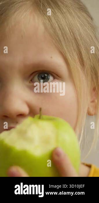 Close up Caucasian little girl kid child eating green apple looking at ...