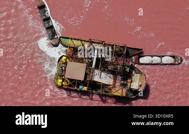 Aerial top view of a salt harvesting barge with cargo boats ...