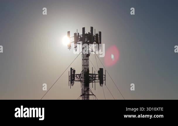 Telecommunication tower with antennas against bright sun and clear blue ...
