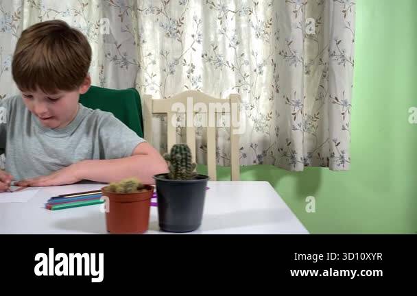 Adorable school-age boy drawing with pencils at home, fully engaged in ...