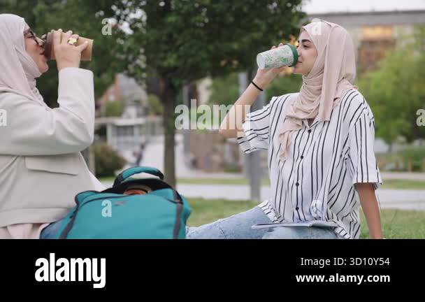 Two cheerful young muslim women in hijabs enjoying a coffee break ...